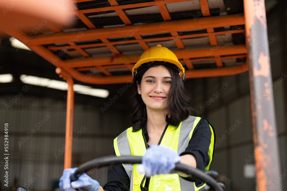 Beautiful female worker driving forklift truck in industrial factory ...