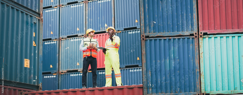 young harbor worker talking on the walkie-talkie at container warehouse ...