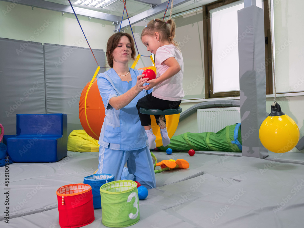 Child with physiotherapist on swing during sensory integration session ...