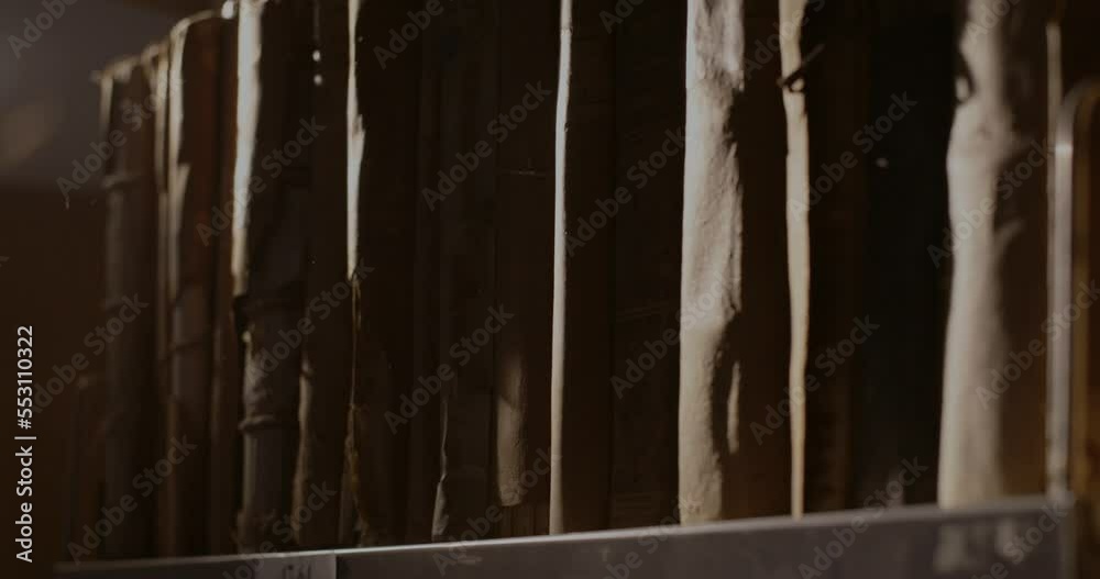 An atmospheric moody close-up shot of a bookshelf full of ancient, old ...