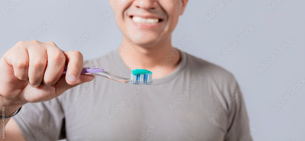 Young man showing toothbrush with toothpaste isolated, guy holding ...