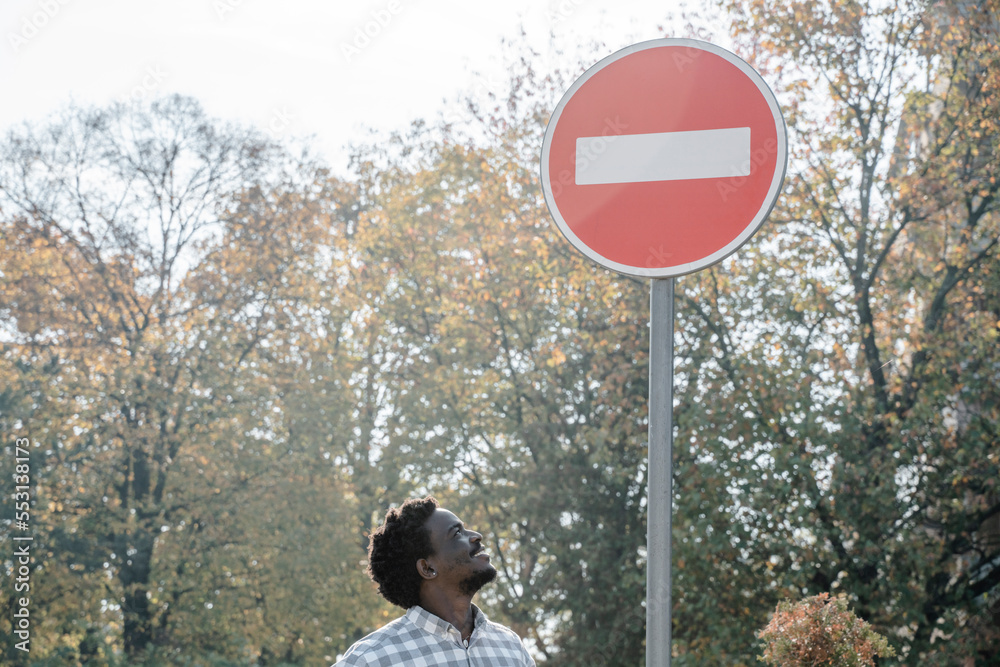 Smiling man looking at no entry sign board Stock Photo | Adobe Stock