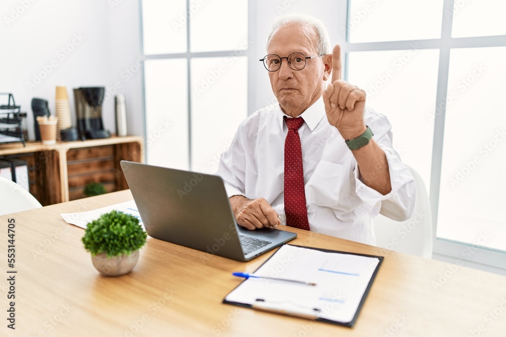 Senior man working at the office using computer laptop pointing with ...