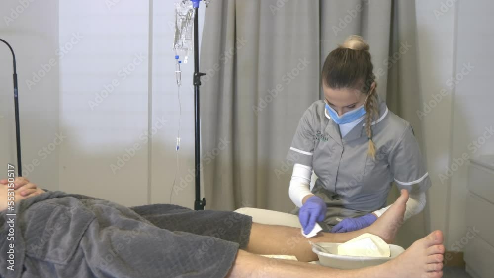 Male patient lying on a hospital bed and young pretty female nurse ...