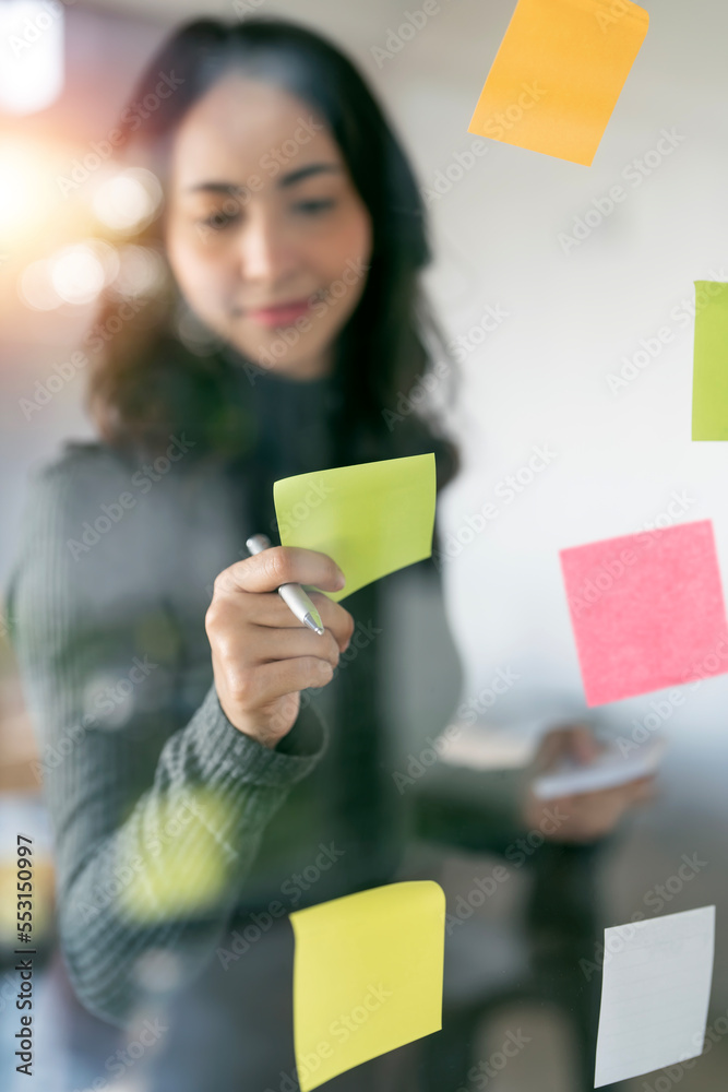 Young smiley attractive, businesswoman using post it notes in glass ...