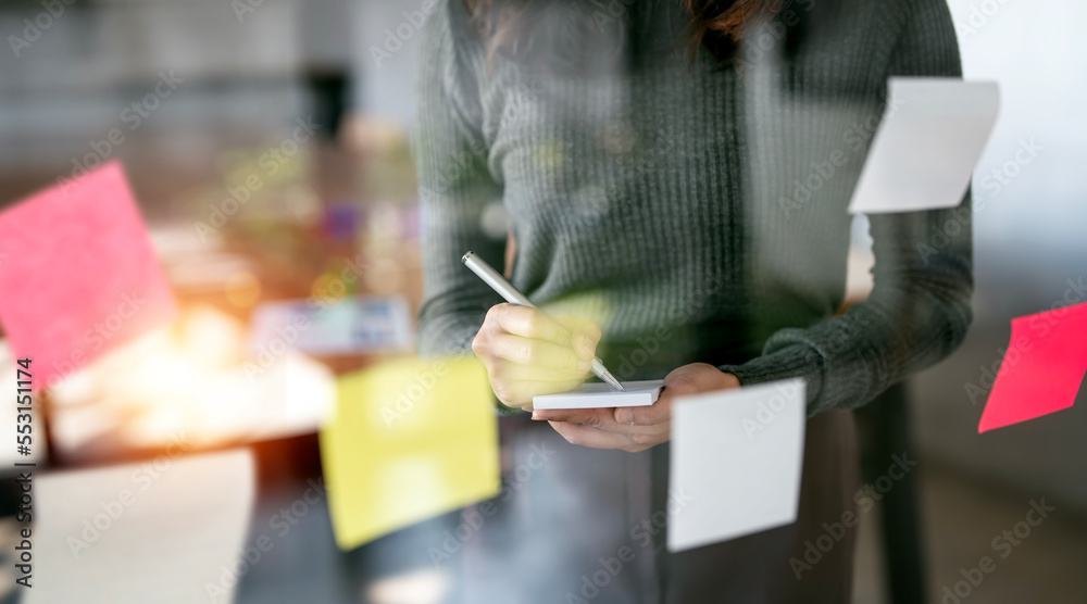 Young creative businesswoman writing note and using post it notes in ...