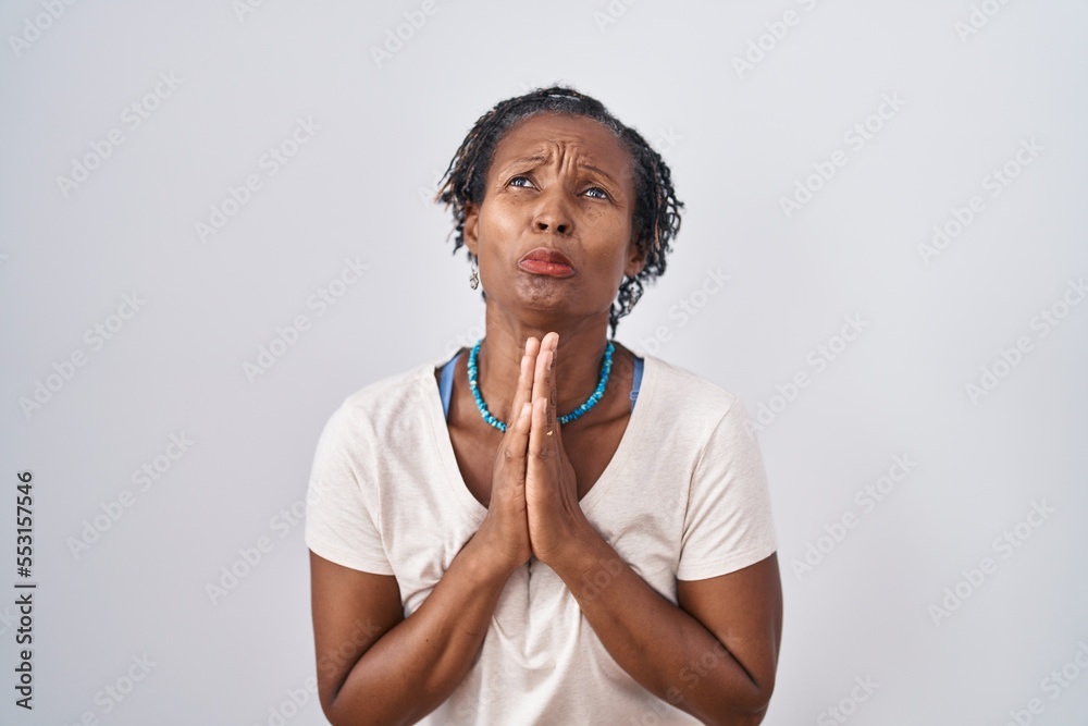 African woman with dreadlocks standing over white background begging ...