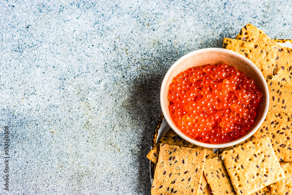 Bowl of red trout fish caviar with flax and sesame seed crackers Stock ...