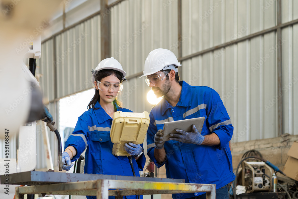 Two male and female engineer working with robot arm system welding at ...