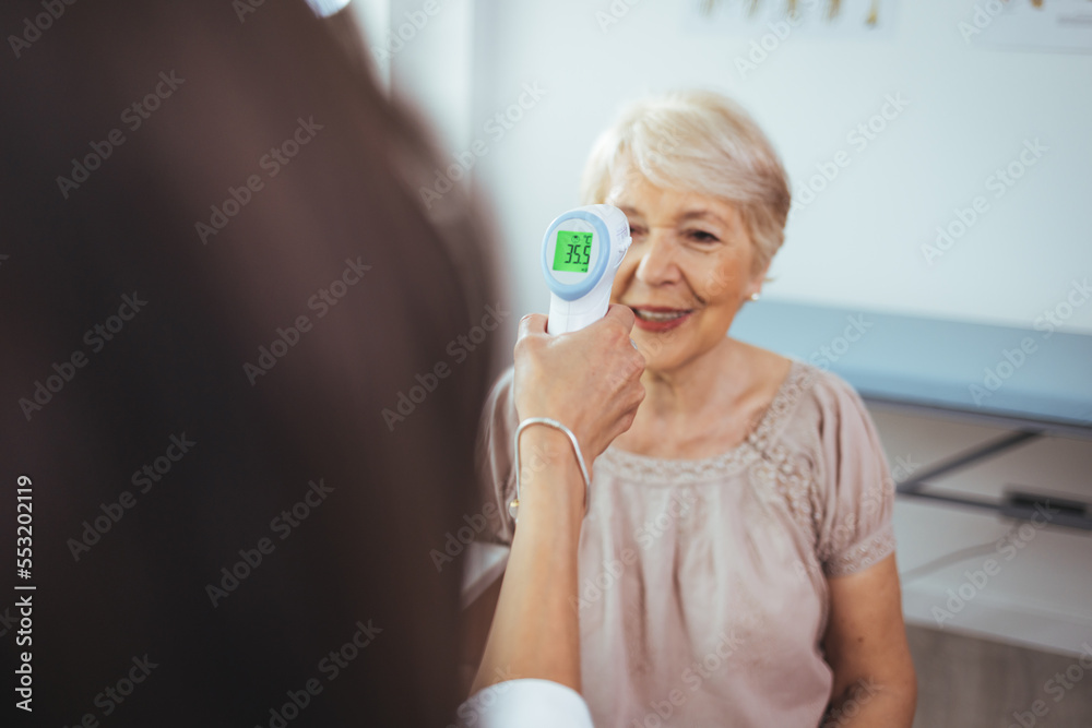 Young nurse or doctor taking patient's body temperature with non ...