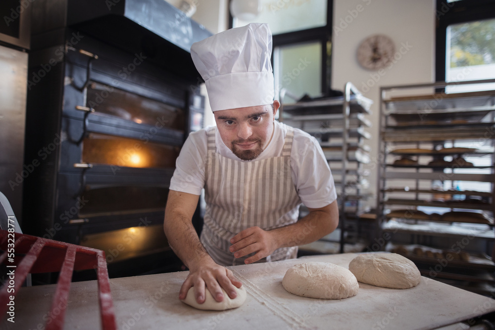 Young baker with down syndrome preparing pastries in bakery. Concept of ...