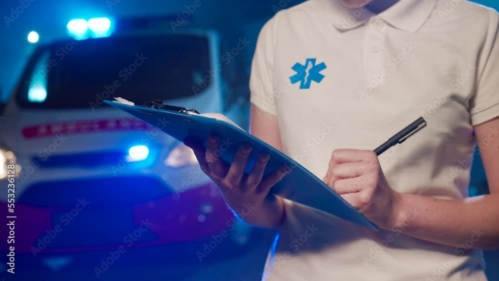 Close-up of professional female paramedic filling writing working with ...