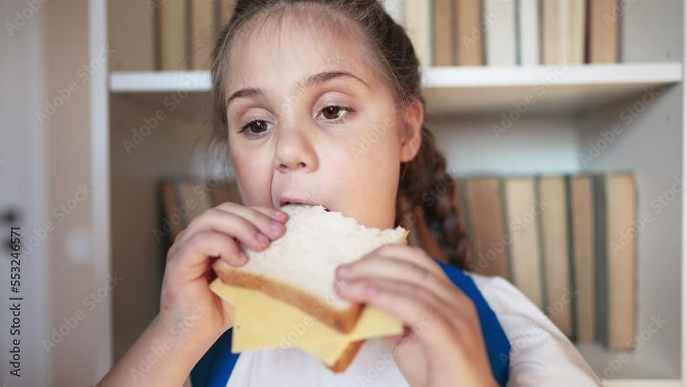 schoolgirl eats a sandwich at school during recess with backpack and ...