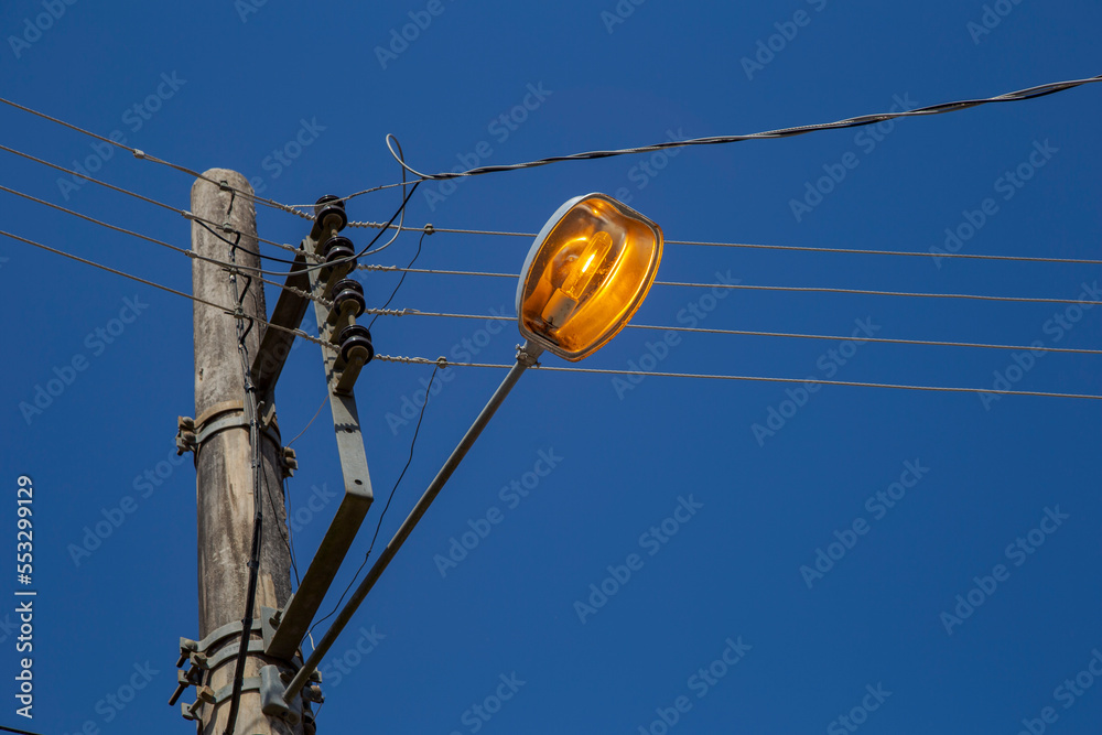 Poste de concreto de iluminação pública com luz acesa durante o dia em ...