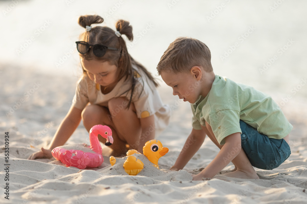 Children boy and girl playing on the beach on summer holidays. Children ...