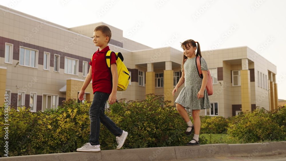 child boy girl walk along curb balance with their hands. jets school ...