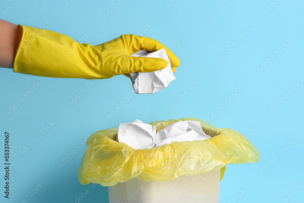 Woman throwing crumpled paper into rubbish bin on color background ...