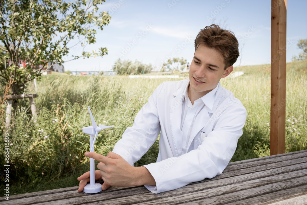 young scientist, student with model of wind turbine standing outside in ...