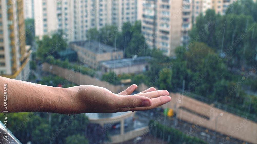 Human hand of an young man under rain. Raindrops slowly falls onto ...