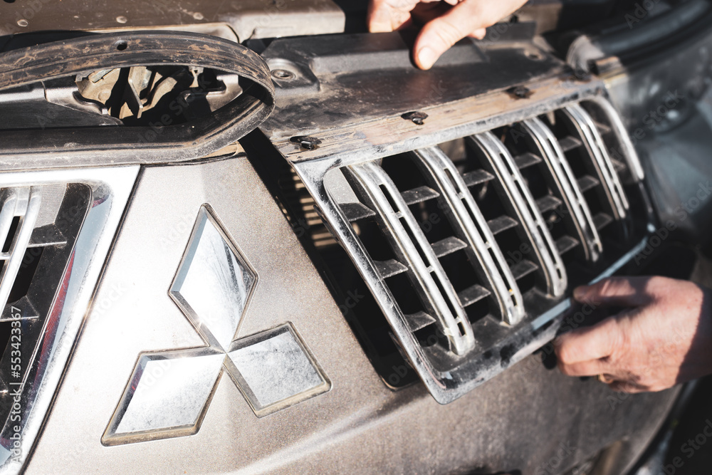 Auto repair. installation of a radiator grille diffuser on a Mitsubishi ...