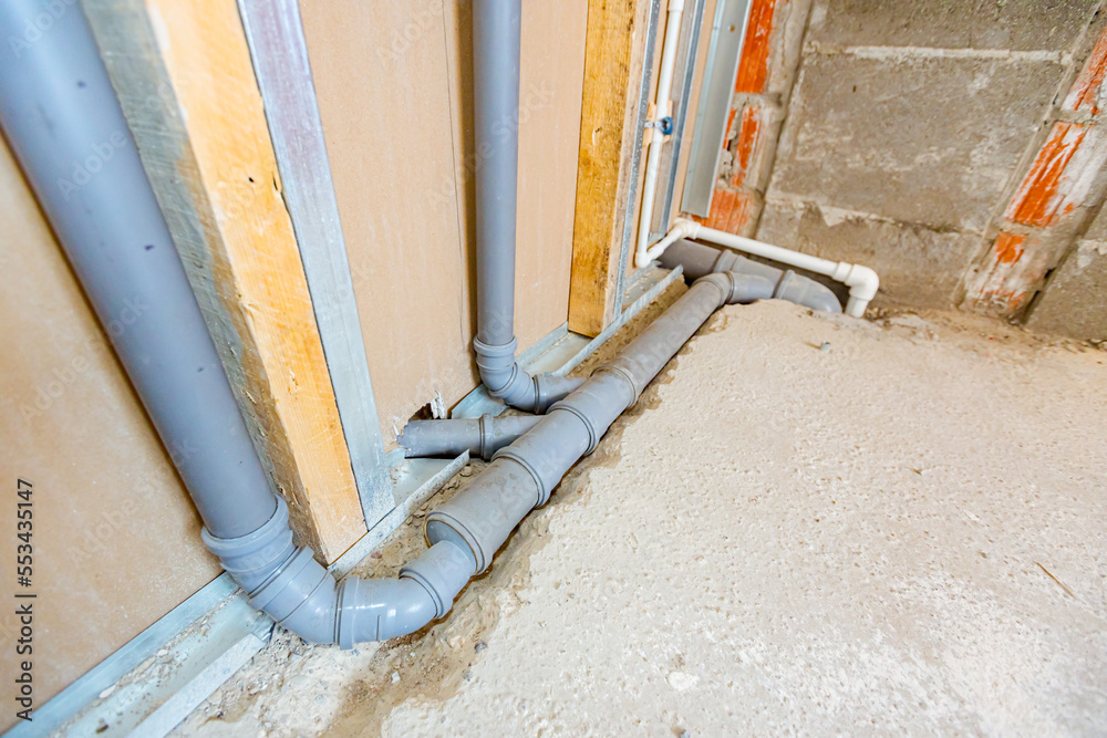 System of gray plastic sewage pipes installed on the gypsum wall for ...