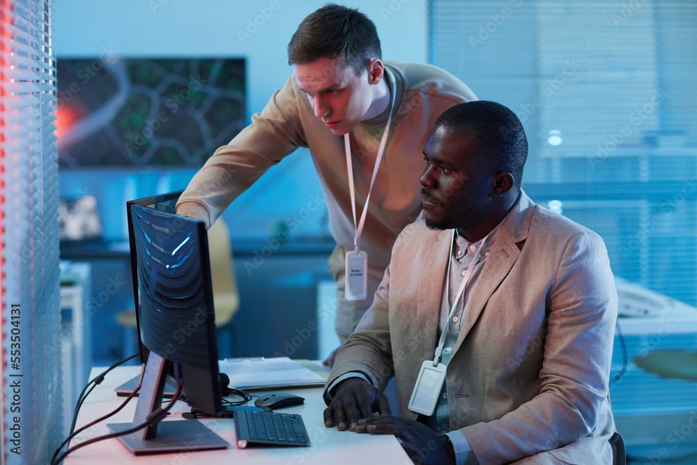 Side view portrait of two people looking at surveillance camera footage ...