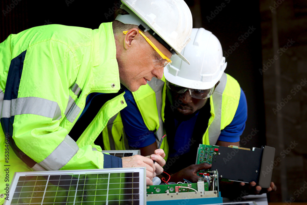 Two electrical engineers working with electronic circuit board and ...