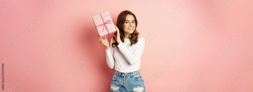 Cute smiling girl guessing whats inside pink present box, shaking gift ...