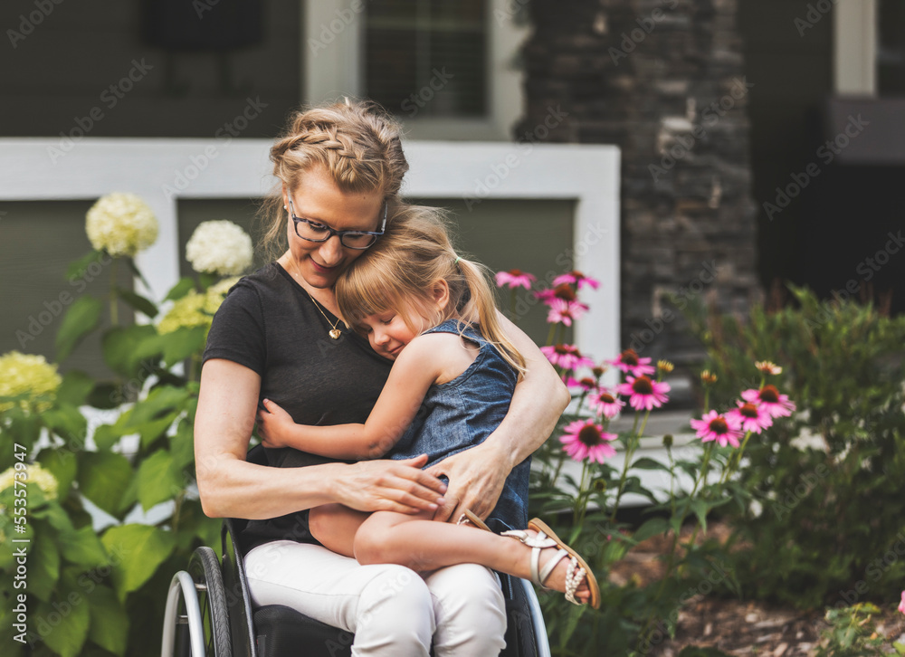 A paraplegic mom holding her little girl in her lap while sitting in ...