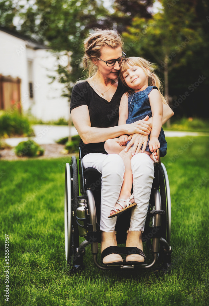A paraplegic mom holding her little girl in her lap while sitting in ...