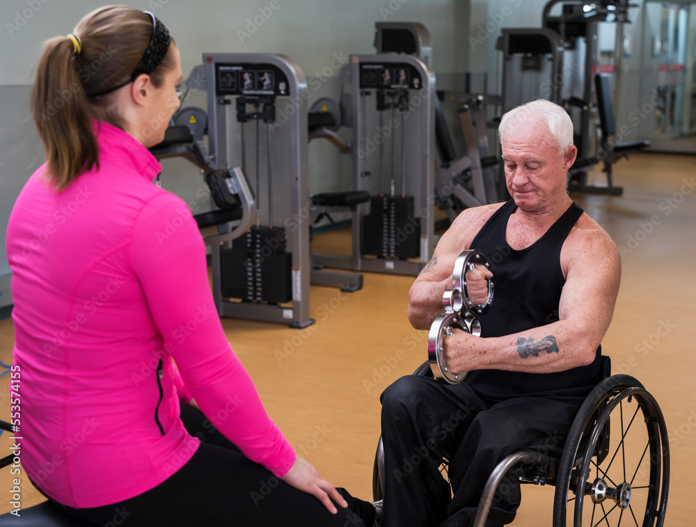 An older paraplegic man working out using a circular handheld device ...