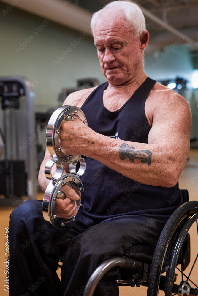A senior paraplegic man working out using a circular handheld device in ...