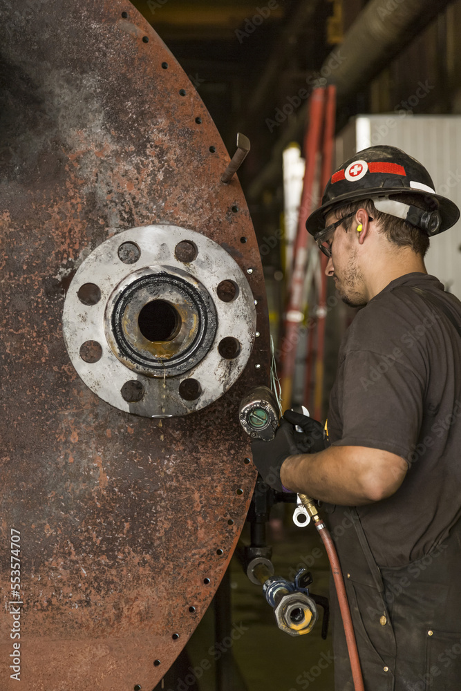 Tradesman bolting up the face plate of a line heater during ...