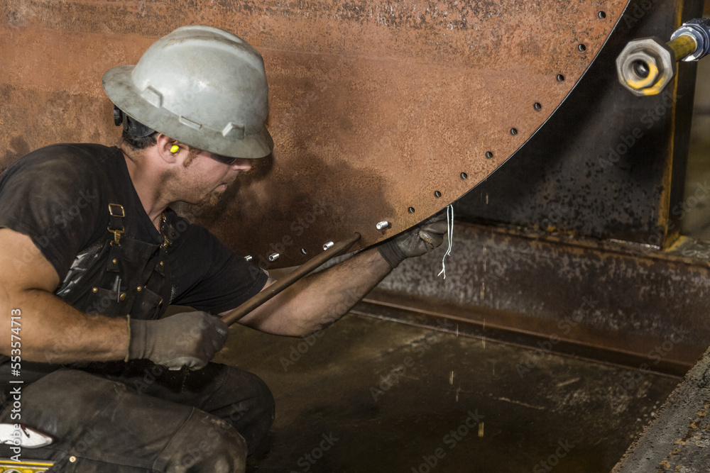 Tradesman bolting up the face plate of a line heater during ...