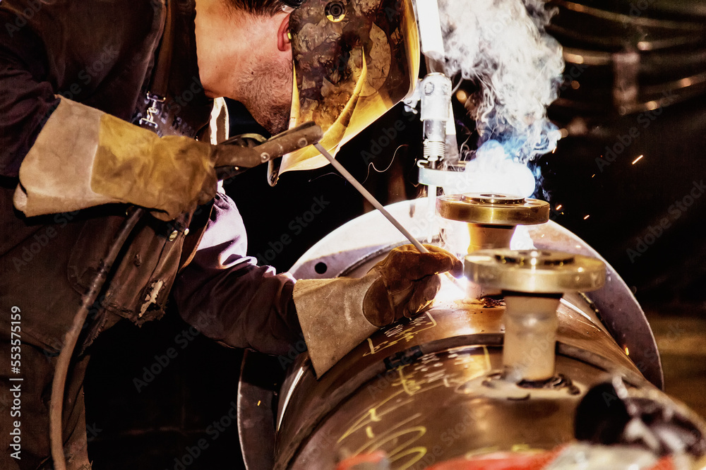 Journeyman tradesman welding a nozzle into a three phase separator at a ...