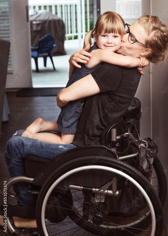 A paraplegic mother holding her daughter on her lap in her wheelchair ...