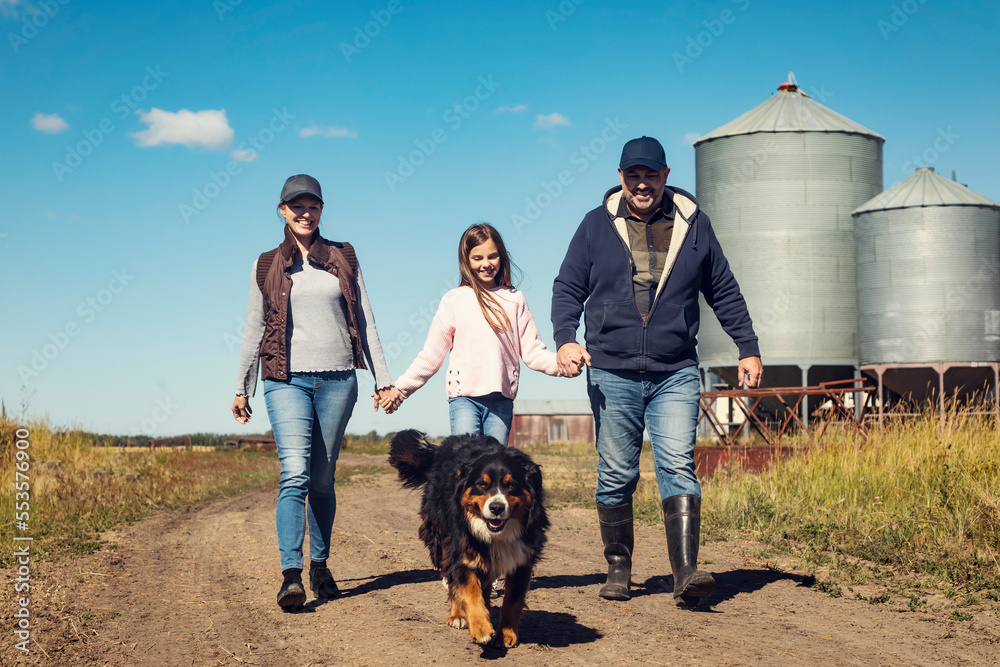 Parents and their young daughter walking on a dirt road with their pet ...