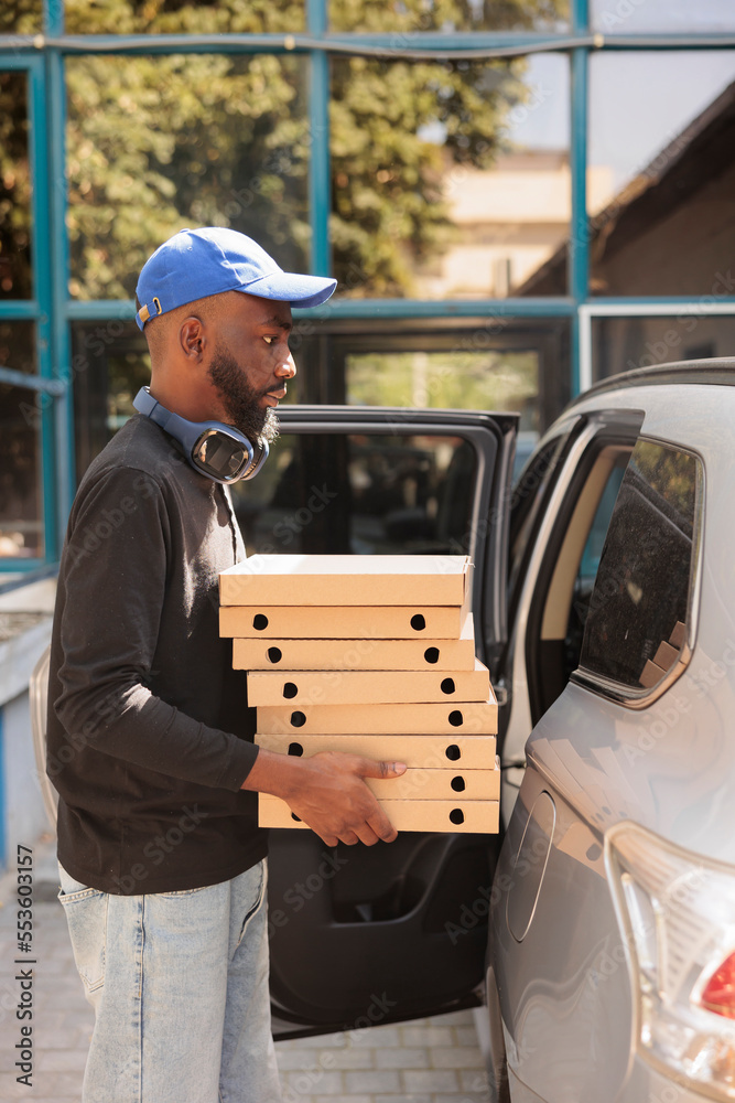 African american courier carrying pizza to office by car side view ...