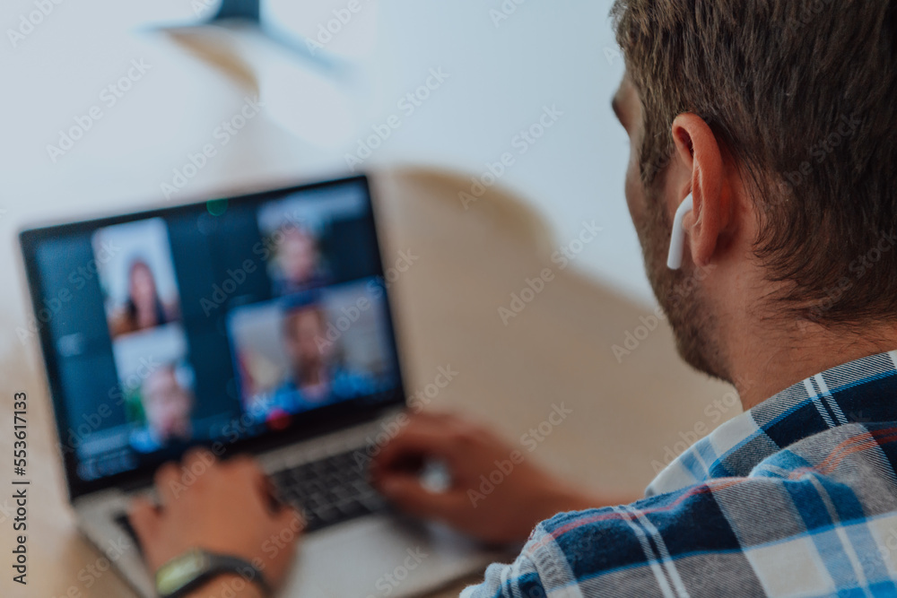 The man sitting at a table in a modern living room, with headphones ...