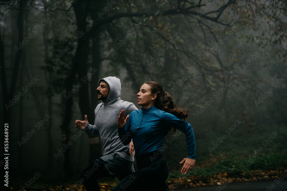 Woman and man in sports outfits in a full sprint on the forest road ...