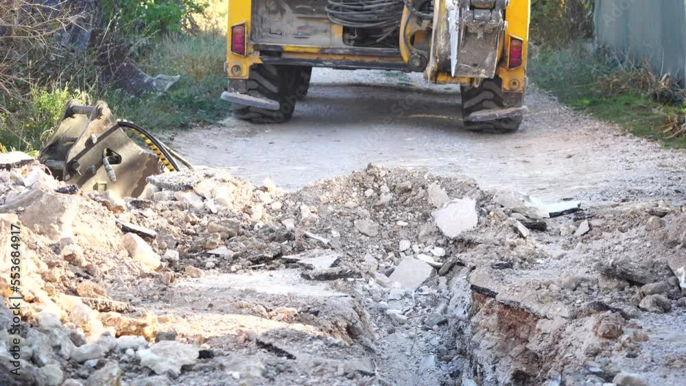 Excavator loudly digs a trench to lay pipes. Close up of an excavator ...