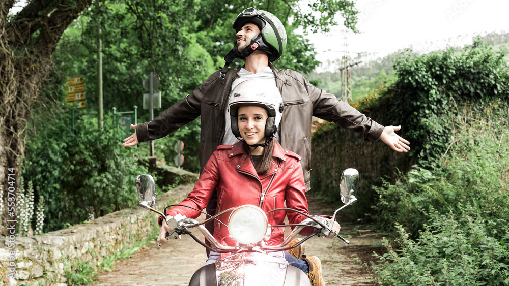 Young couple on motorcycle with child passenger raising arms feeling ...
