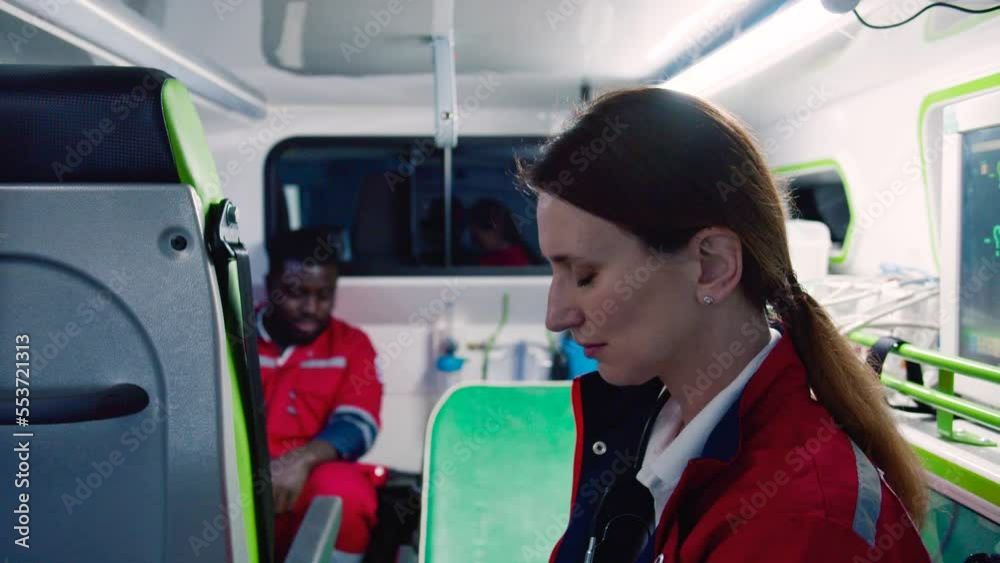 Side-view close-up portrait of tired young female paramedic sitting in ...