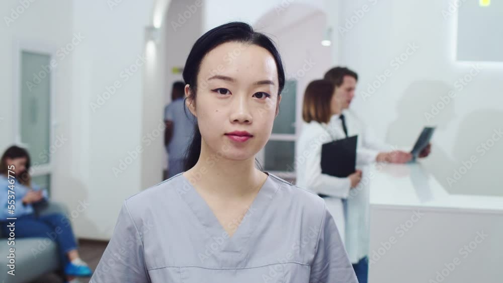 Portrait of young professional female doctor looking at camera wearing ...