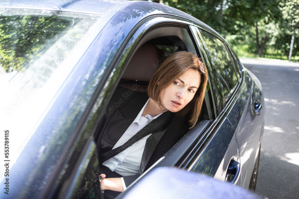 Nervous business woman driving and peeps out of the window of her ...