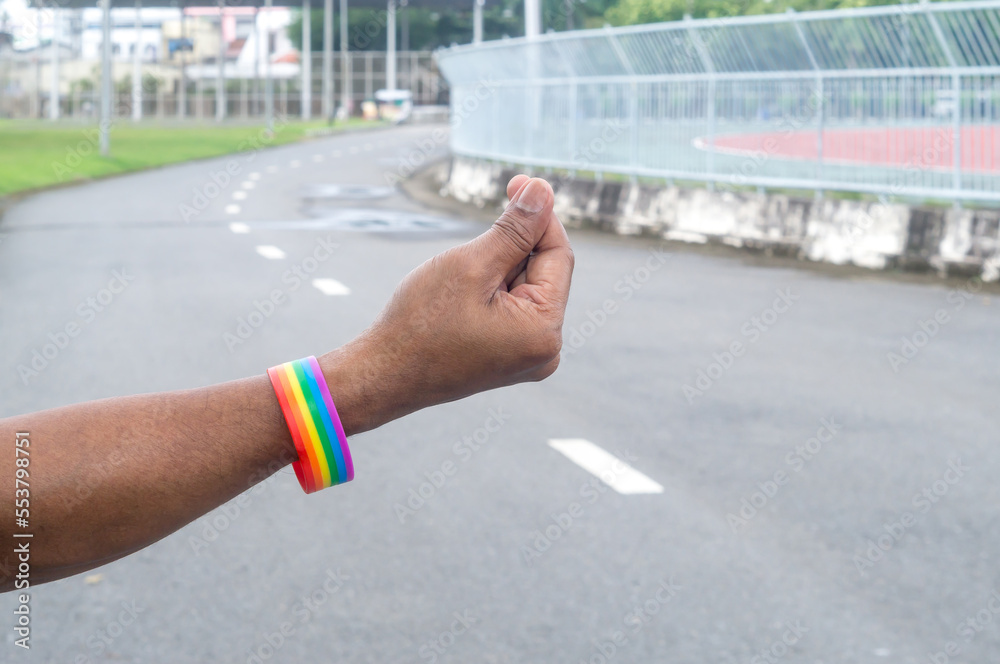 Hand wearing rainbow or lgbtq+ symbol wristband stretching in the air ...