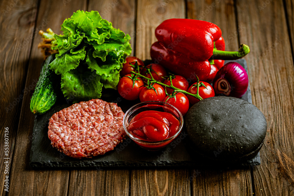 Composition of ingredients for beef black burger on a black stone board ...