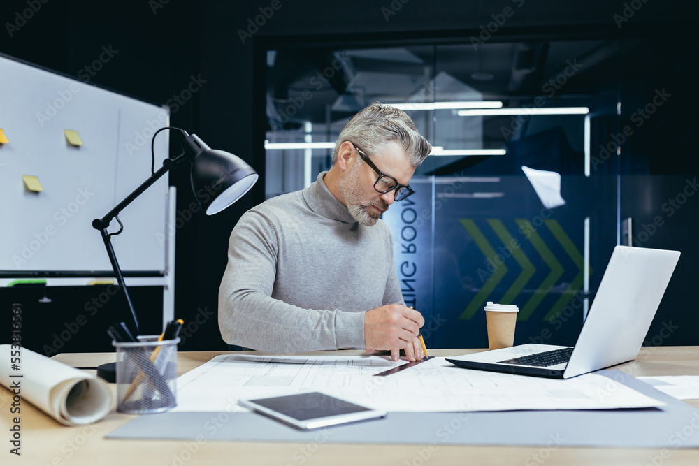 Handsome gray-haired senior man architect, designer, engineer makes a ...