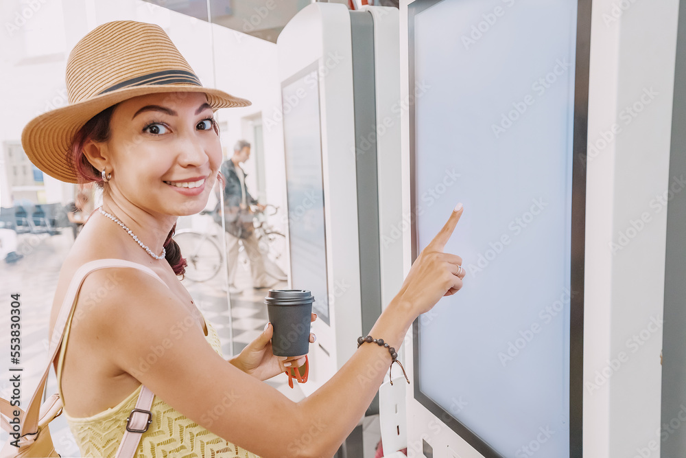 Happy girl customer uses a touchscreen terminal screen or self-service ...