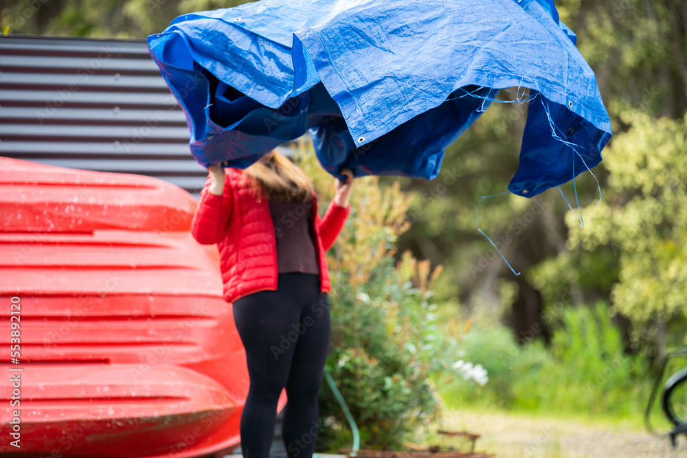 woman folding up a tarp at a campground in australia. camping tant and ...